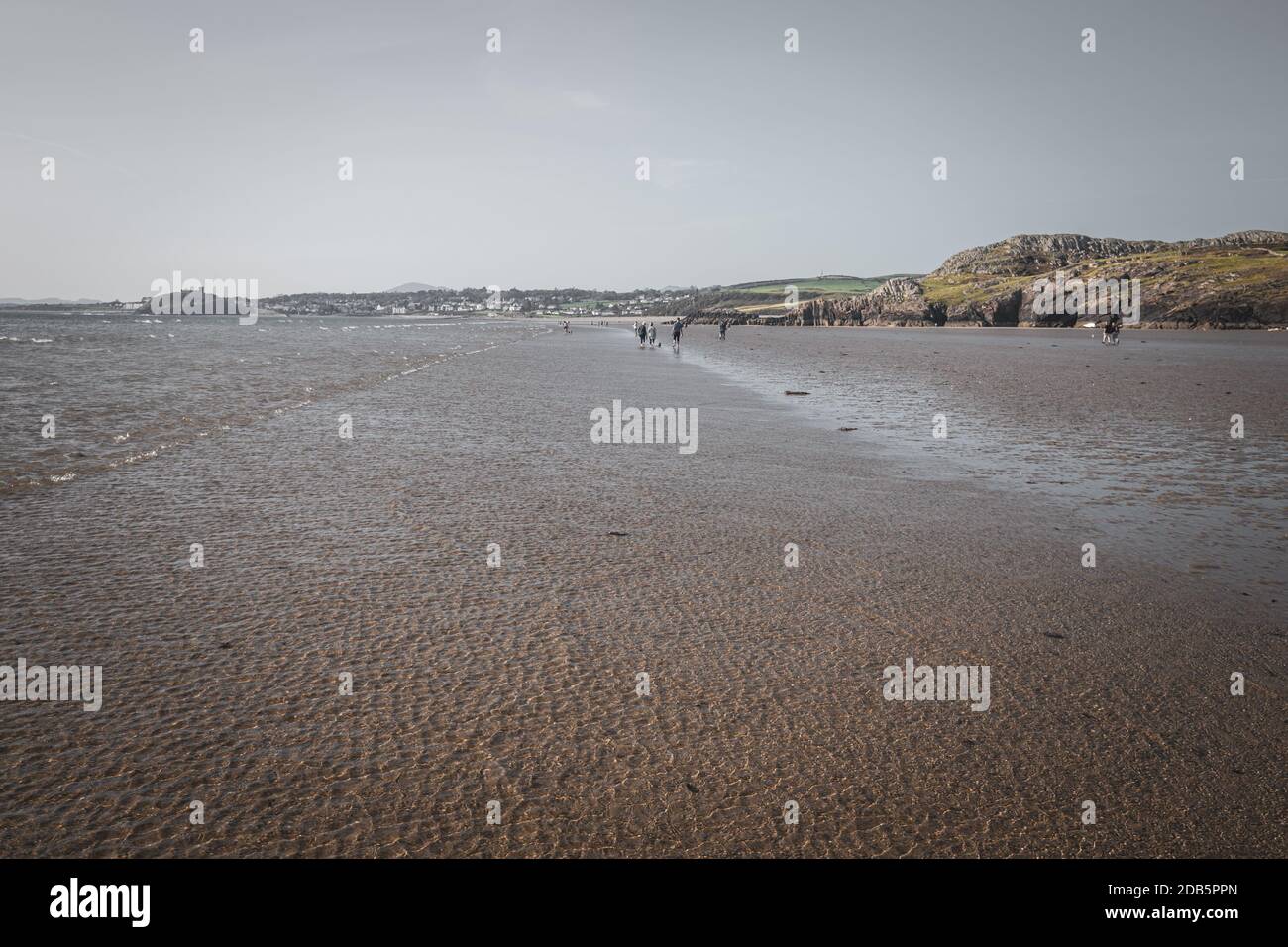 People taking walk along shore of Black Rock Sands beach in North Wales ...