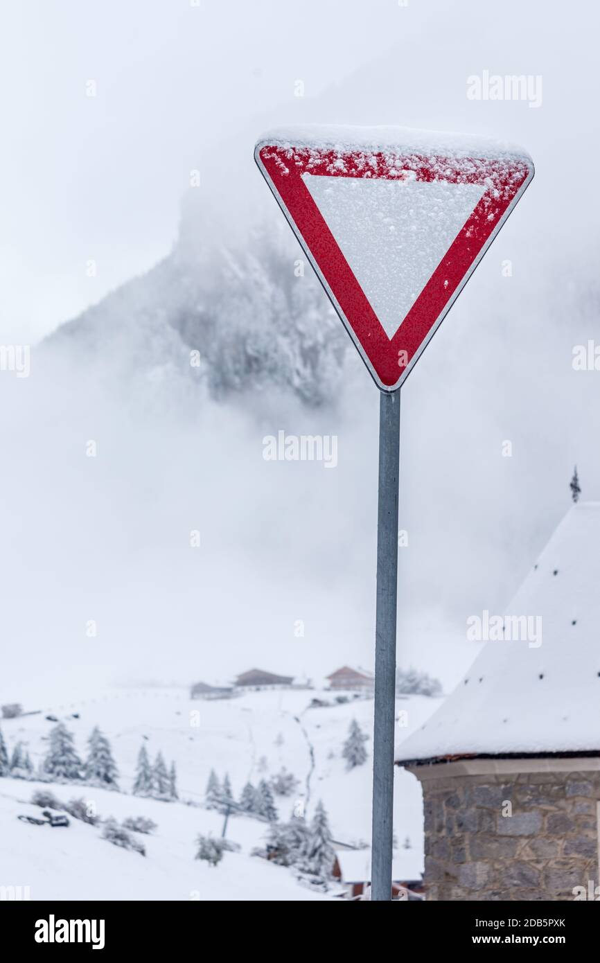 Snowy sign giving way in the Alps, Italy Stock Photo - Alamy