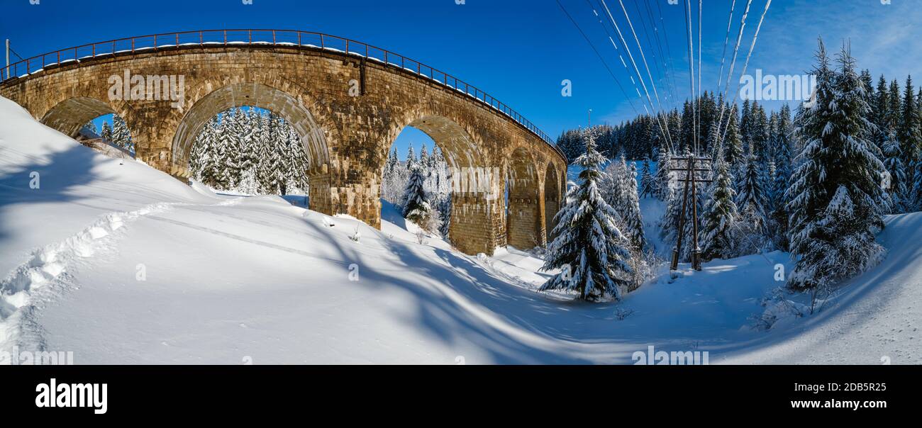 Stone viaduct (arch bridge) on railway through mountain snowy fir ...