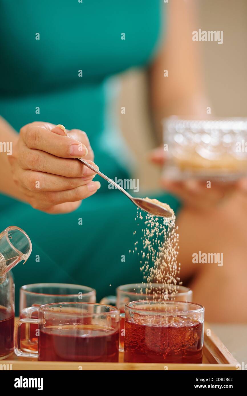 Woman putting sugar in tea cup Stock Photo - Alamy