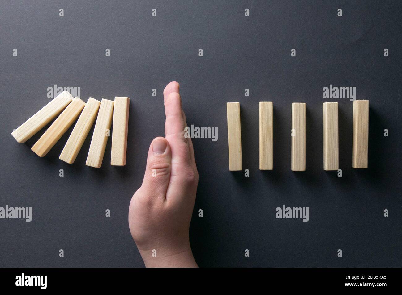 Top view man hand stopping falling dominos in a business crisis ...