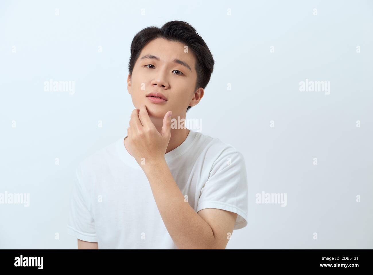 Handsome man. Charming young man keeping hand on chin and smiling while ...