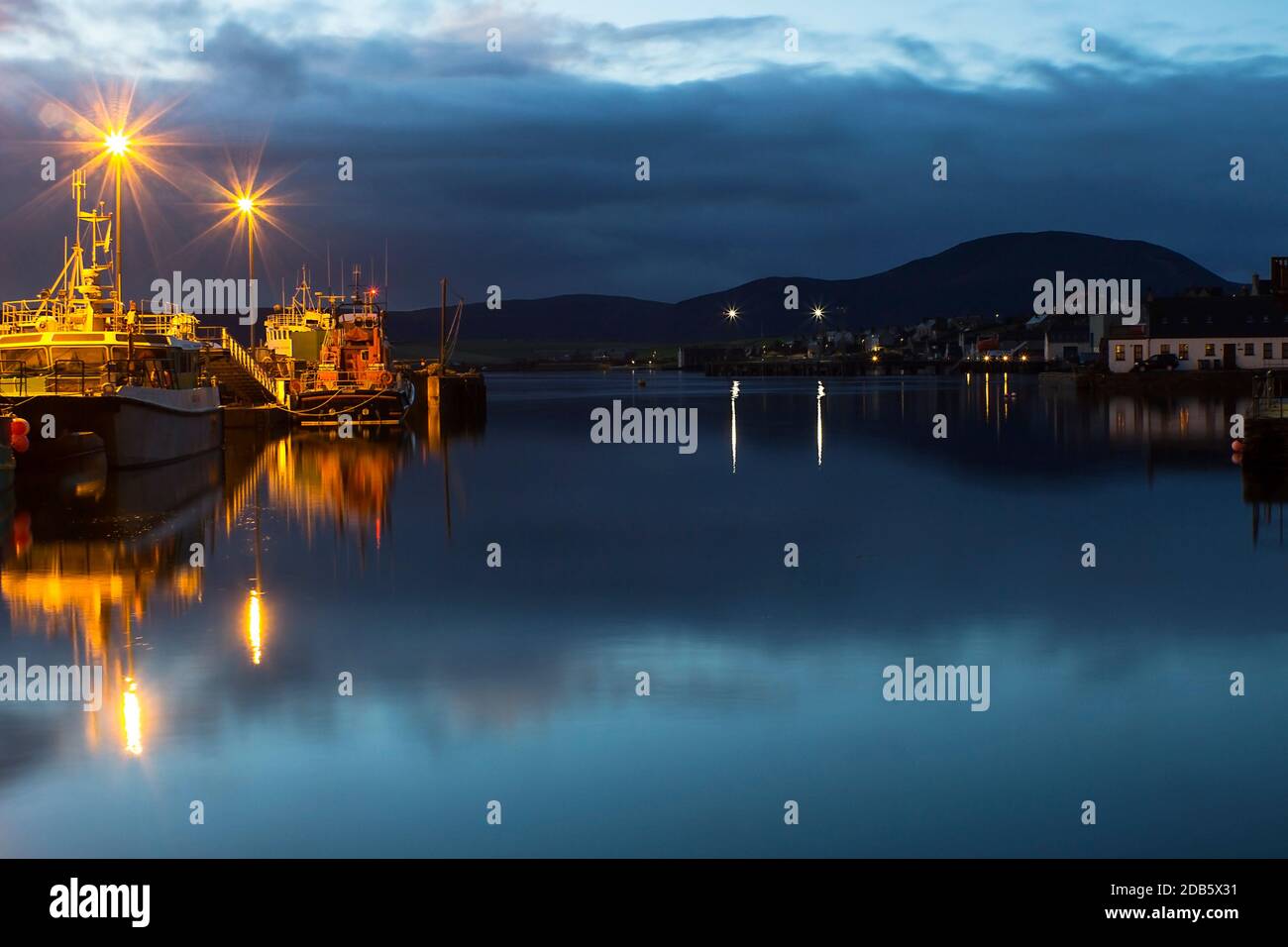 Scottish harbour with boats and lights before sunrise and blue sky ...