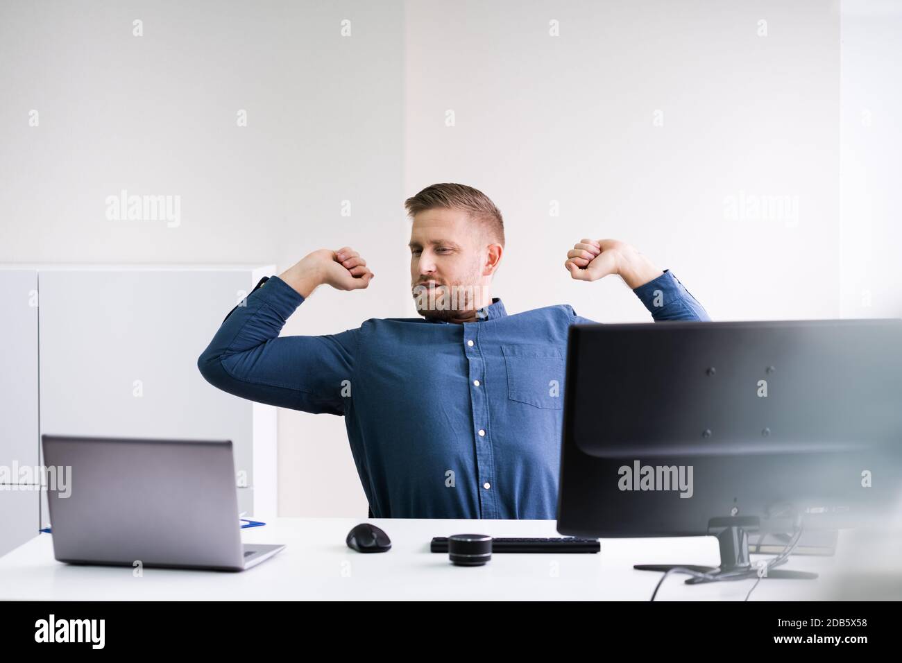 Close-up Of A Young Businessman Stretching His Arms At Workplace Stock ...