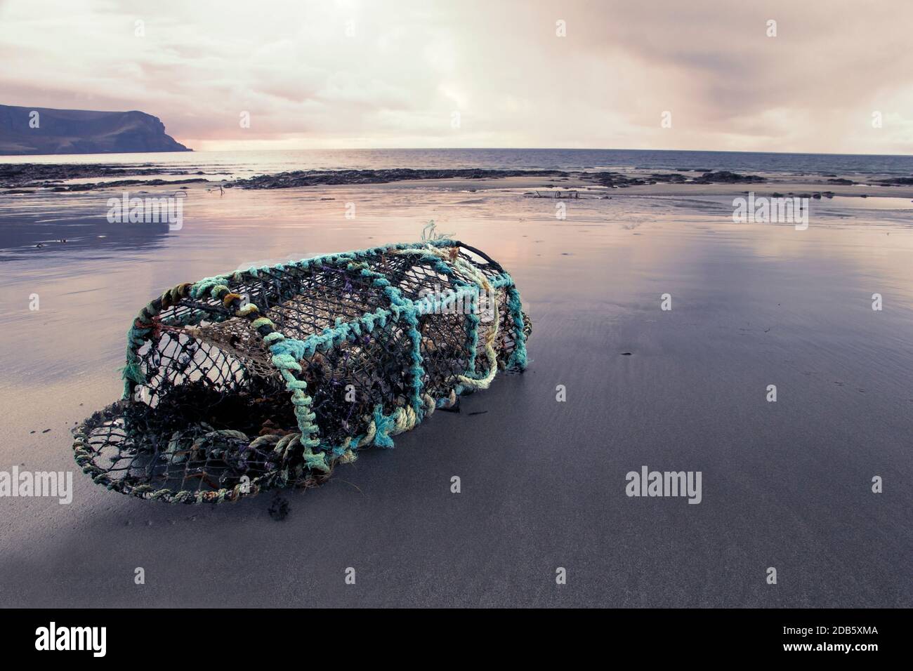 Abandoned open creel cage on sandy scottish beach with hills in ...