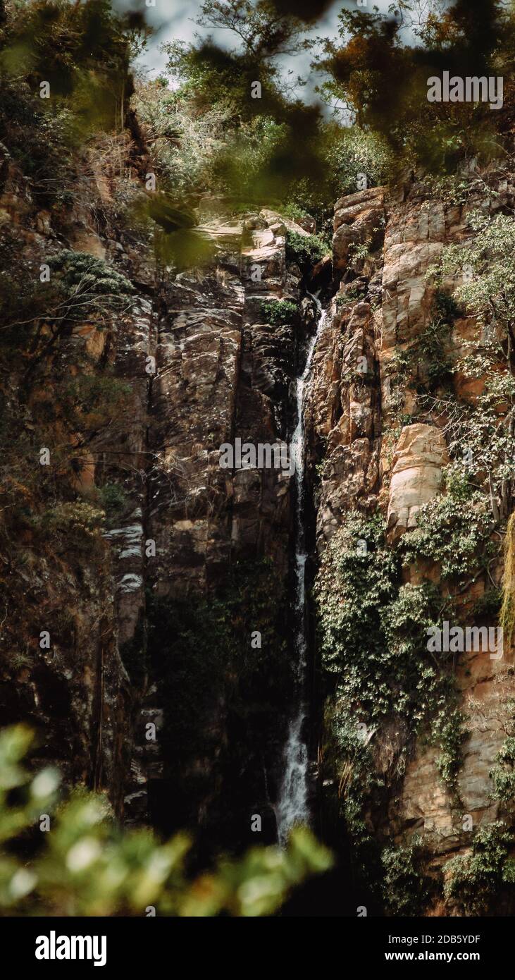 A vertical panoramic view of an immense rough cliff with a long thin ...