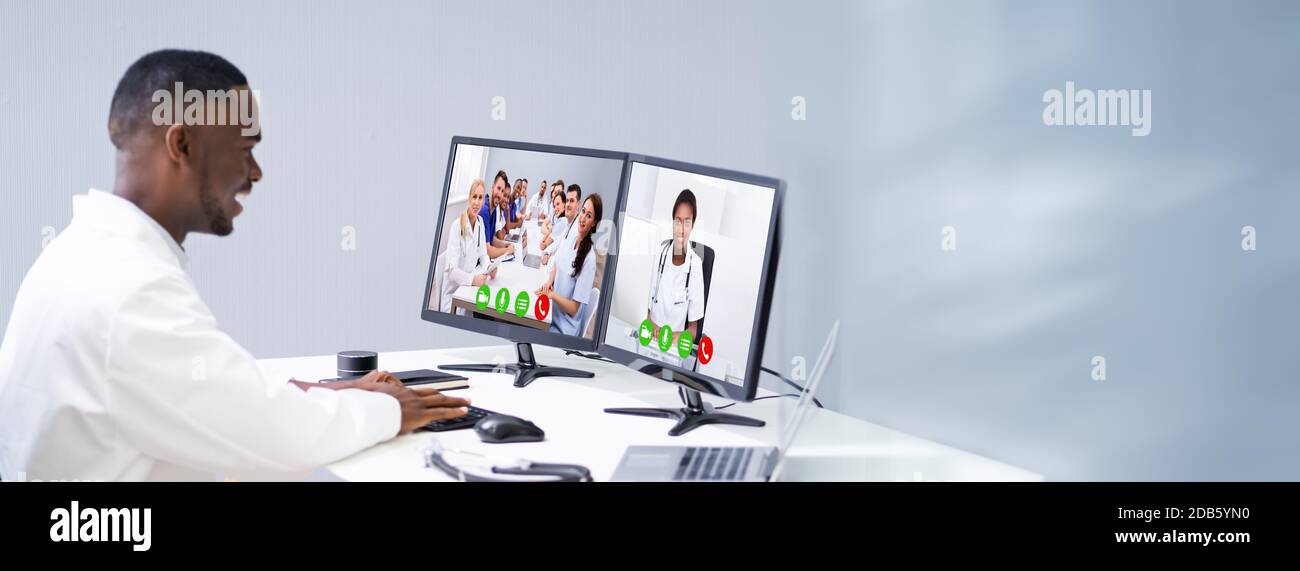 Young Male Doctor Video Conferencing With Medical Team On Computer Desk ...