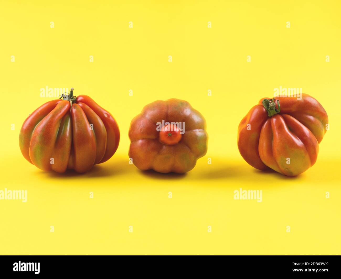 Ugly tomato vegetables on yellow background Stock Photo - Alamy