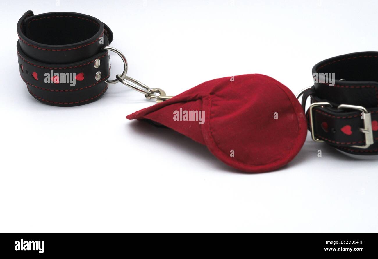 leather handcuffs with chain and ball gag isolated in the white and ...