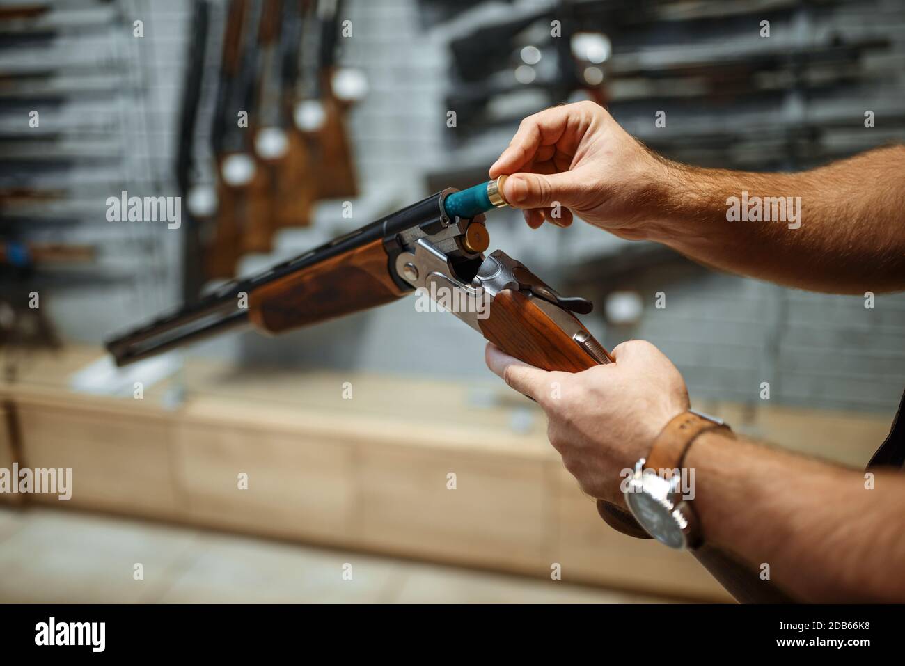 Man loads a rifle, gun shop interior on background. Euqipment for ...