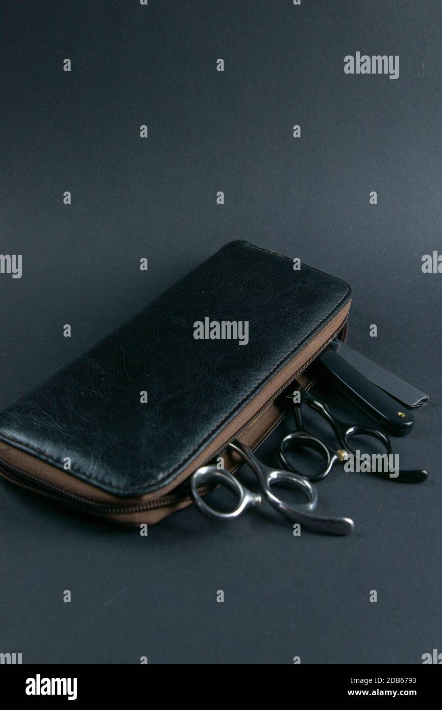 Scissors, combs, a dangerous razor in a special case on black ...