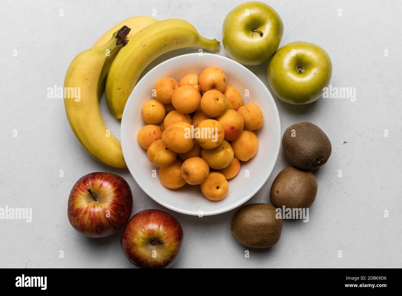 A top view of apricots in the bowl with fresh apples bananas and kiwis ...