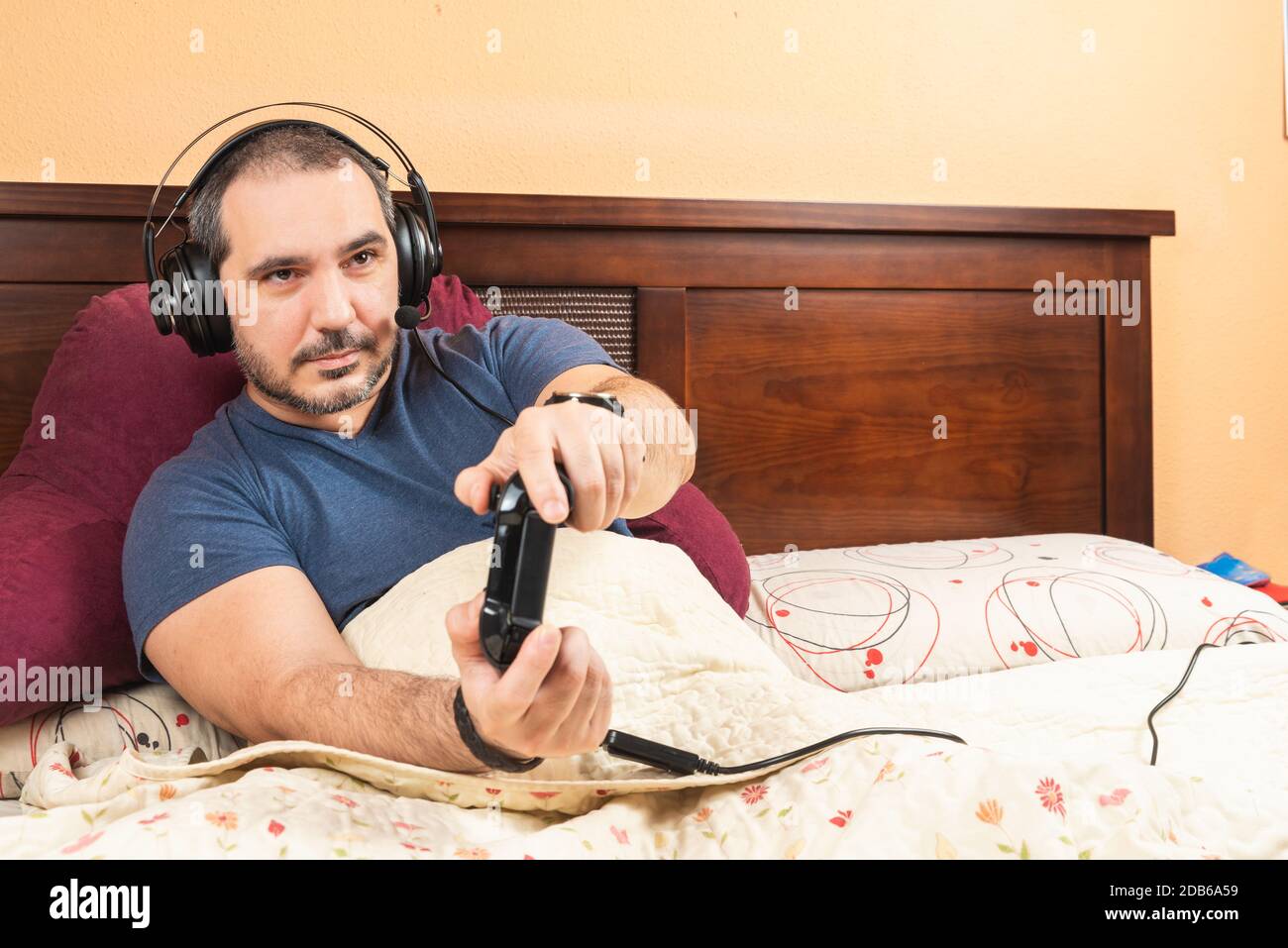 sick man with headphone playing videogames in the bed Stock Photo - Alamy