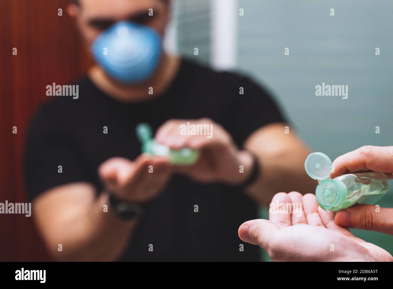 man with face mask applying disinfectant sanitizer onto hand for ...
