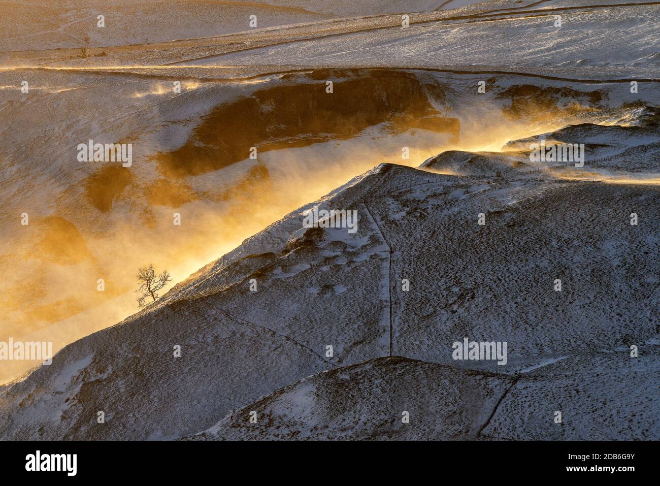 Strong wind blowing snow over ridge of a hill in the Peak District with ...