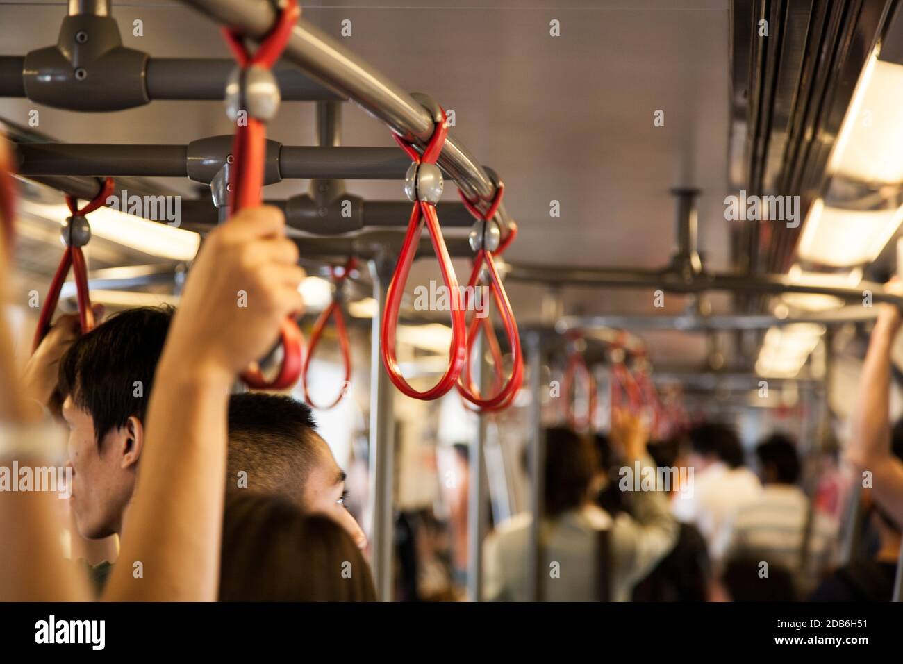 Passengers holding on to hand rails whilst travelling on train around ...