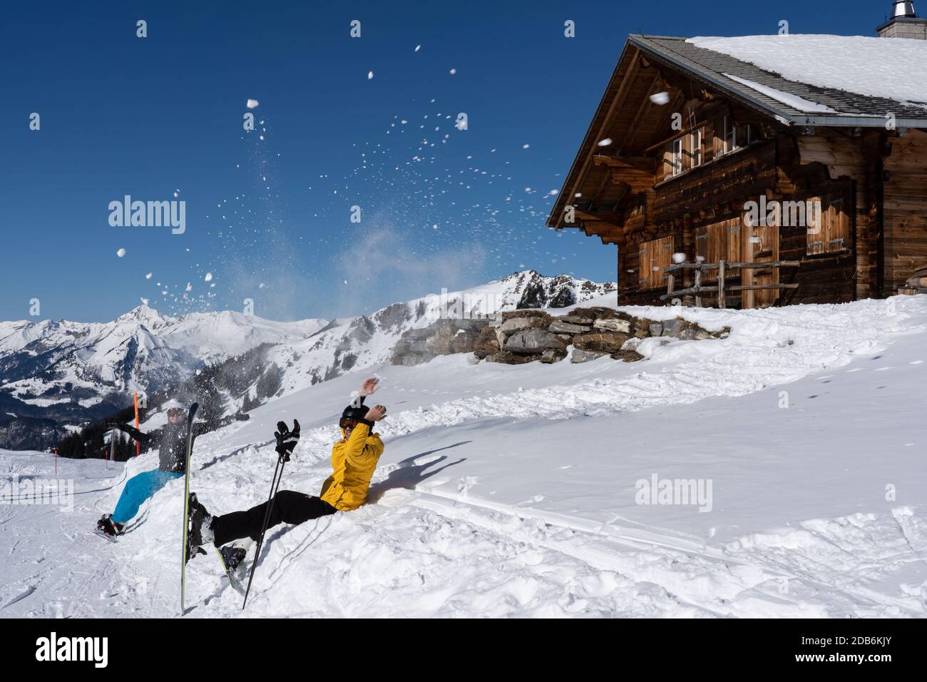 Two happy alpine skier and snowboarder throwing cheerful snow in air in ...