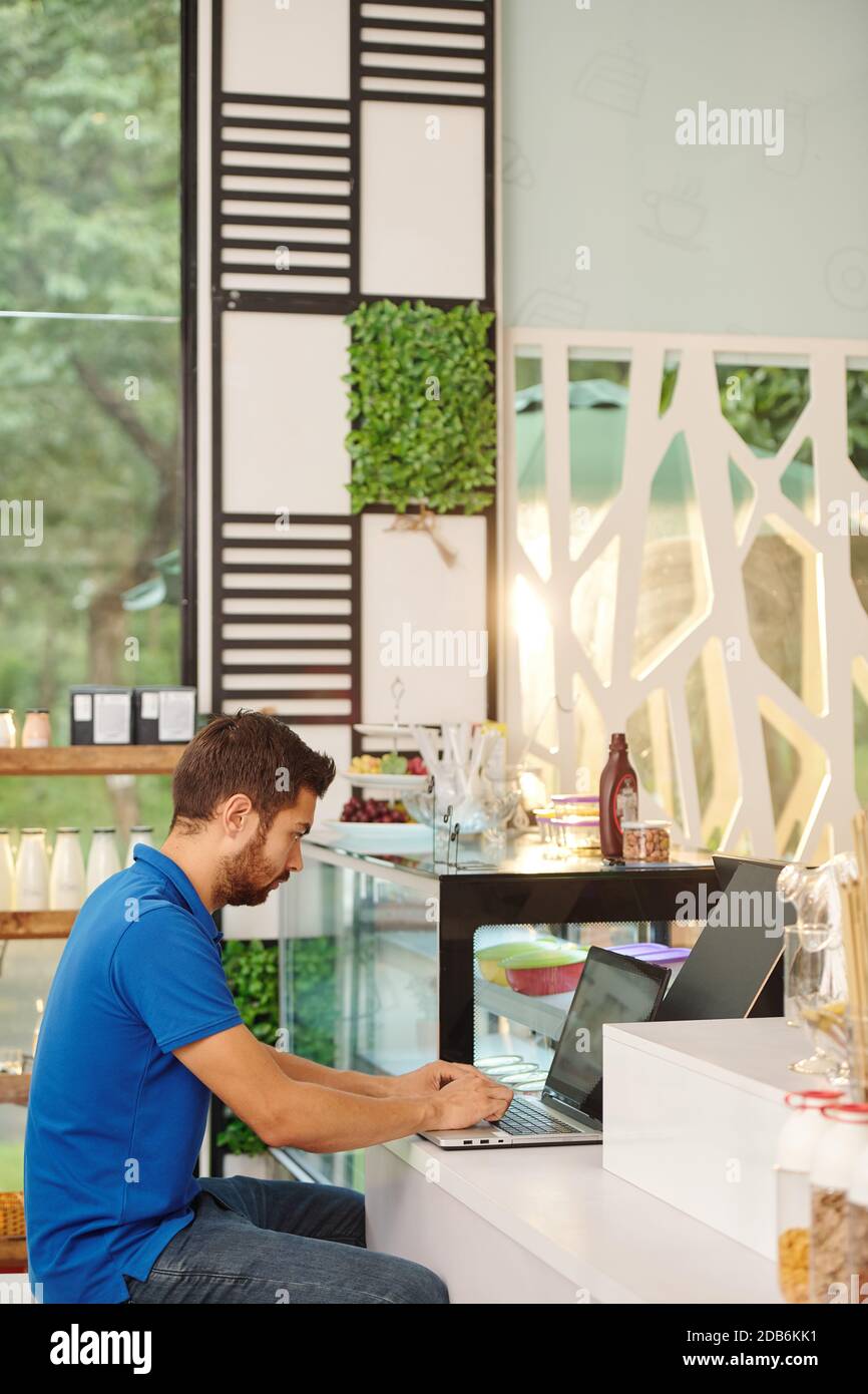Cafe manager working on laptop Stock Photo - Alamy
