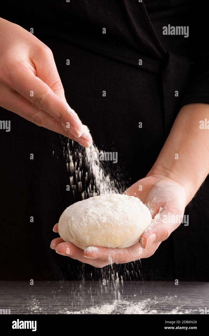 White flour falling on dough in female hands. Cooking and kitchen ...