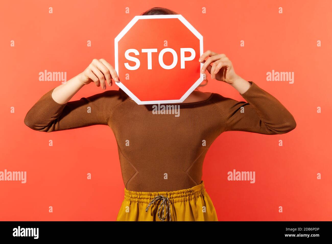 Scared anonymous woman hiding her face behind stop road sign, campaign ...
