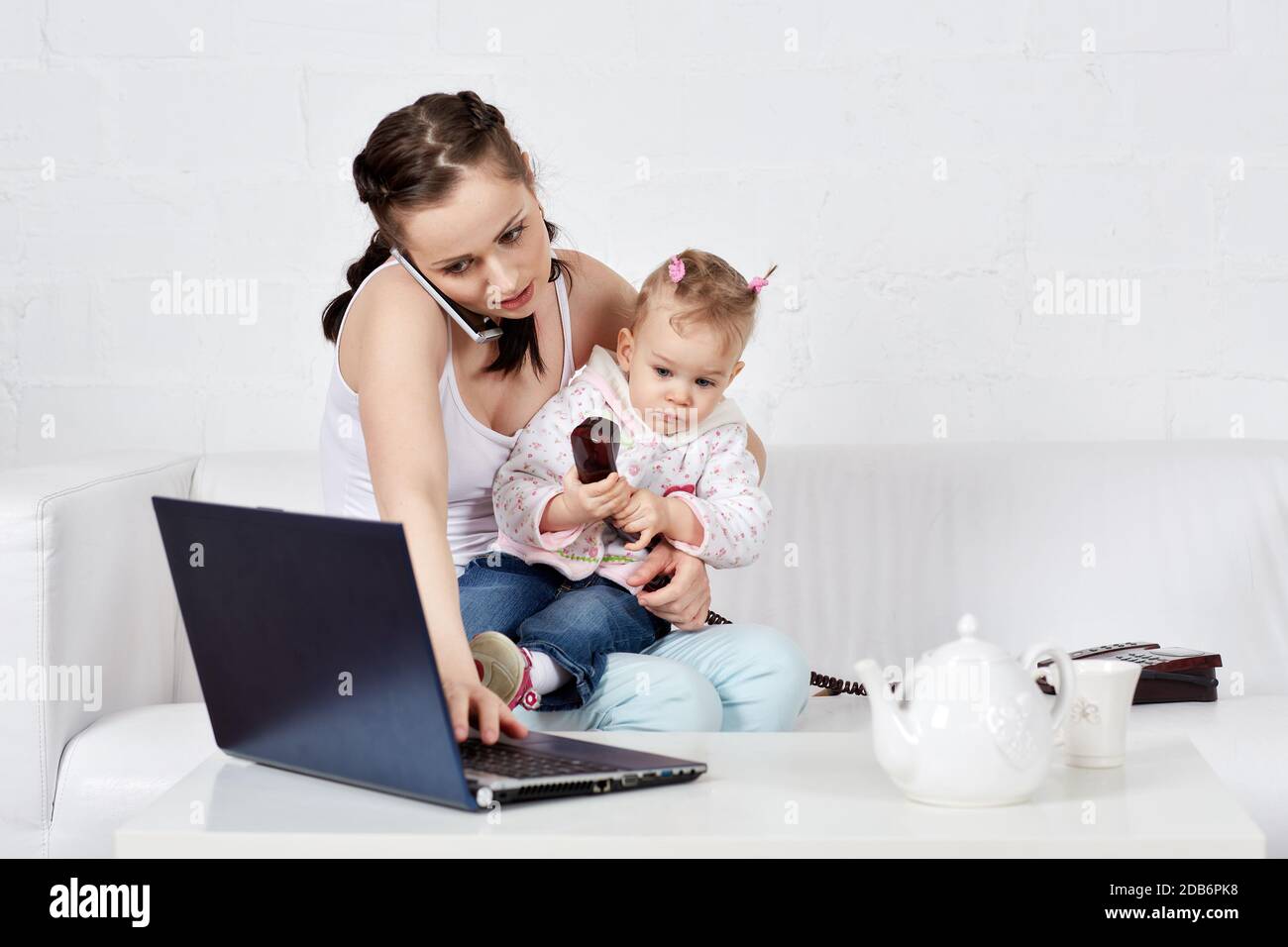Small child and busy young woman with notebook and phone sit on the ...