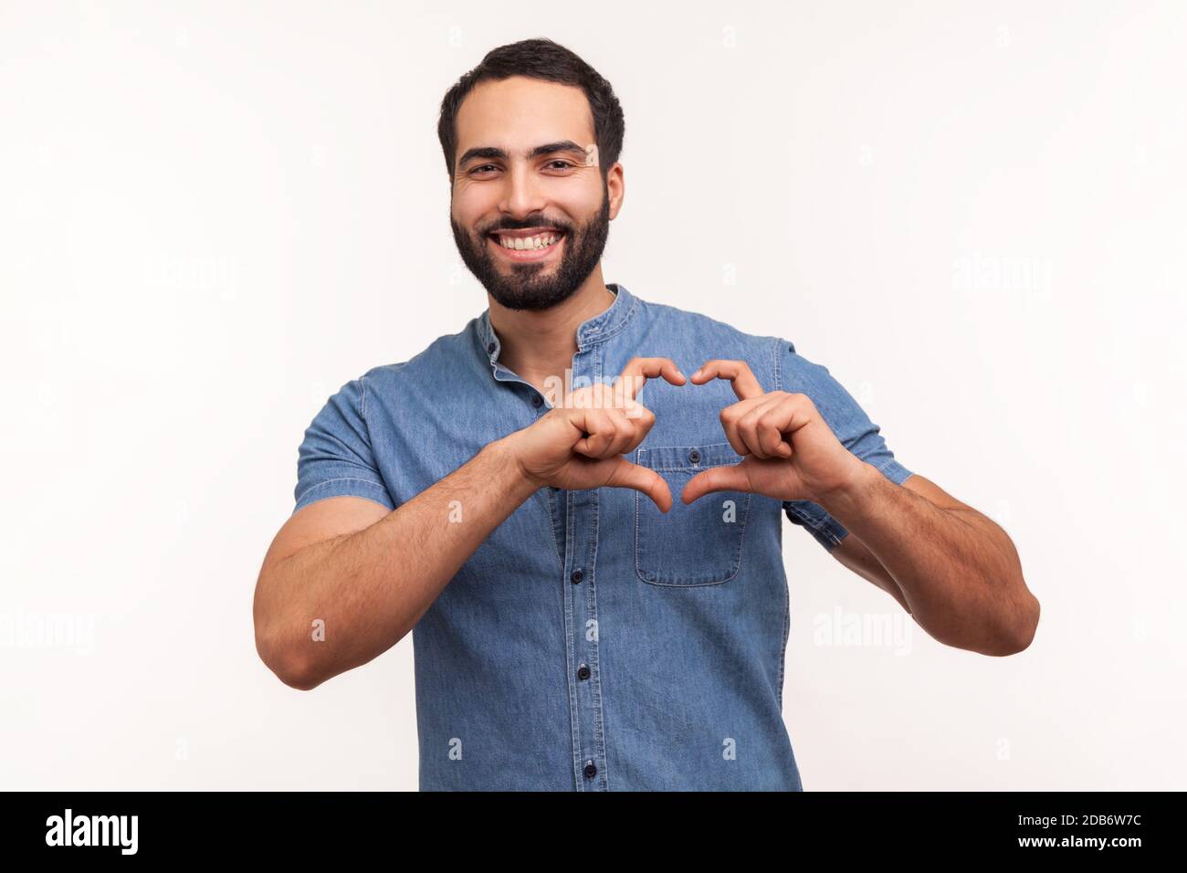 Handsome positive man holding hands in shape of heart showing romantic ...