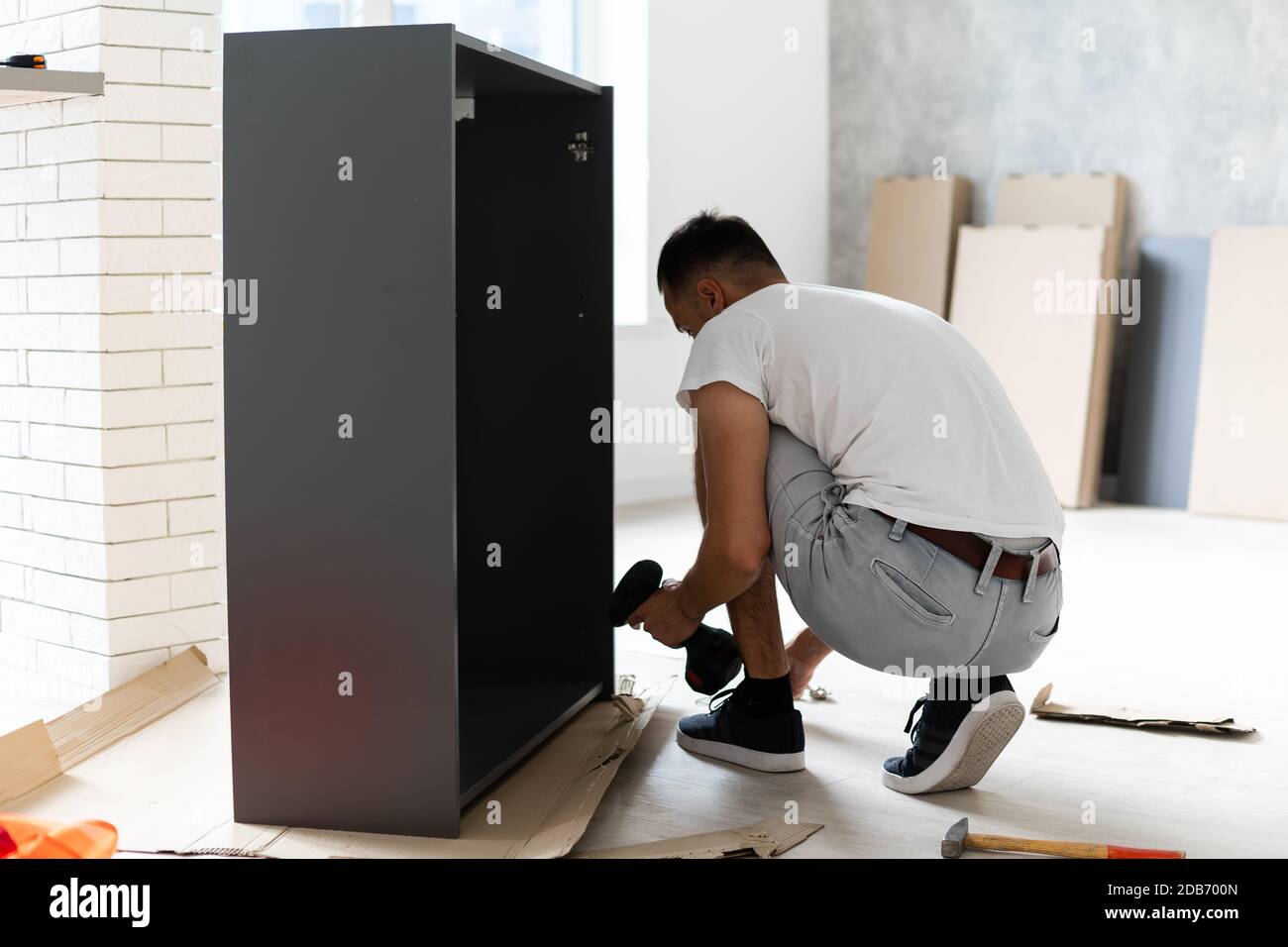 Assembling new wooden furniture by hand in room. Man putting together ...