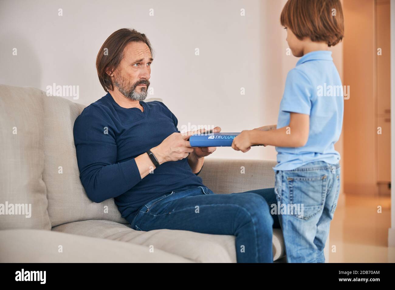 Slightly-annoyed father being too busy to read to his child Stock Photo ...