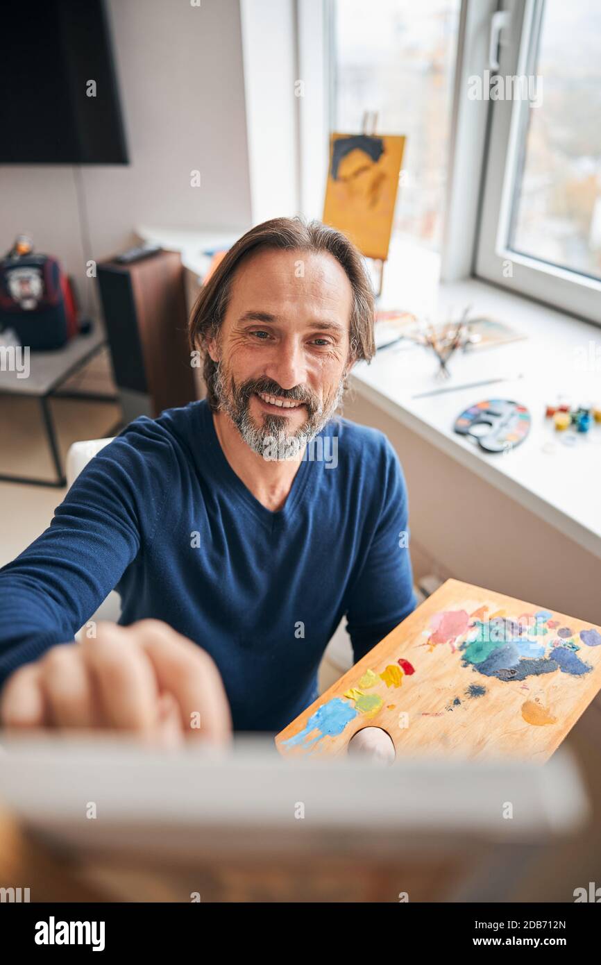 Joyful artist looking satisfied with how his painting turning out Stock ...