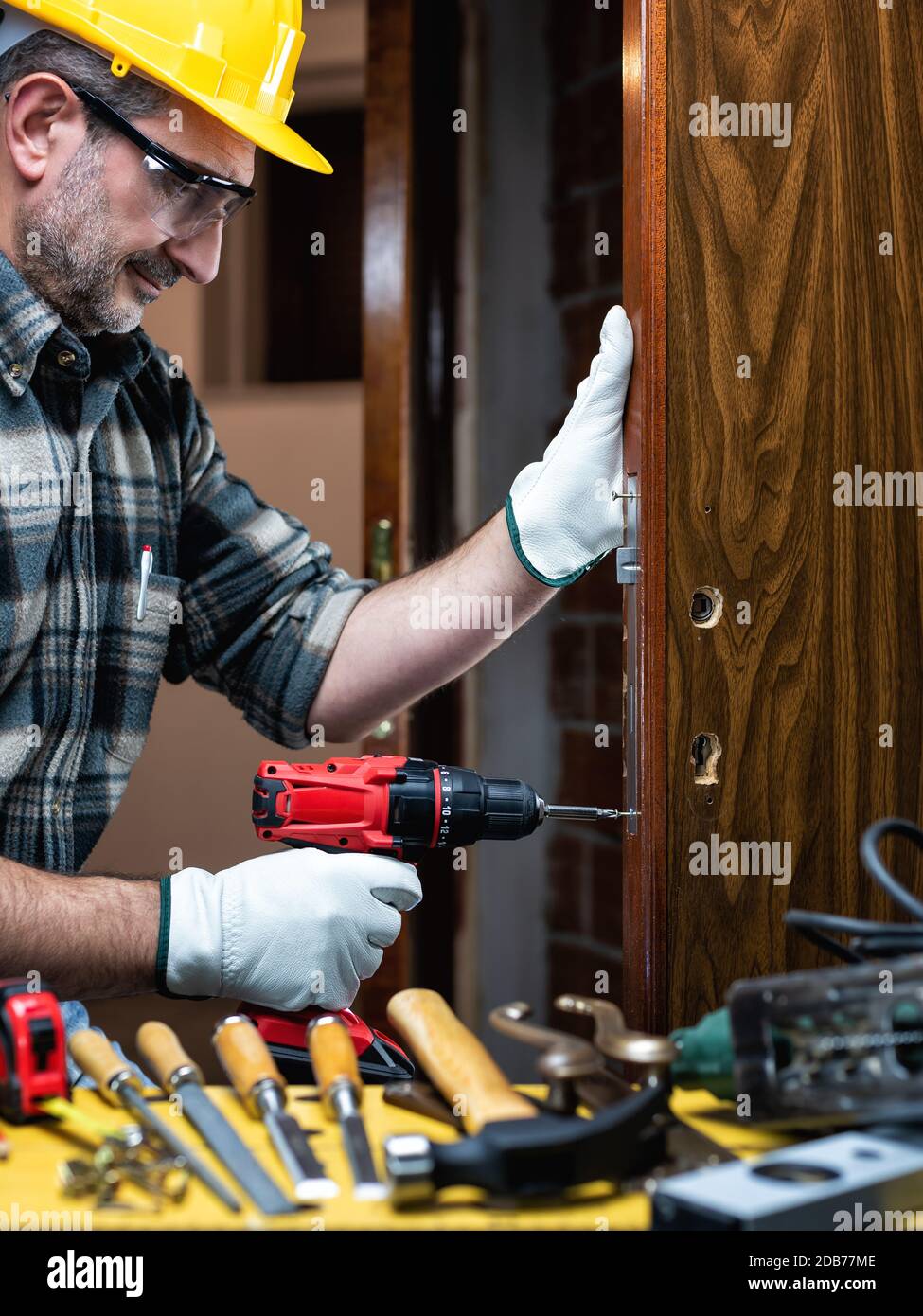 Close-up. Carpenter at work repairs and installs the new lock of a ...