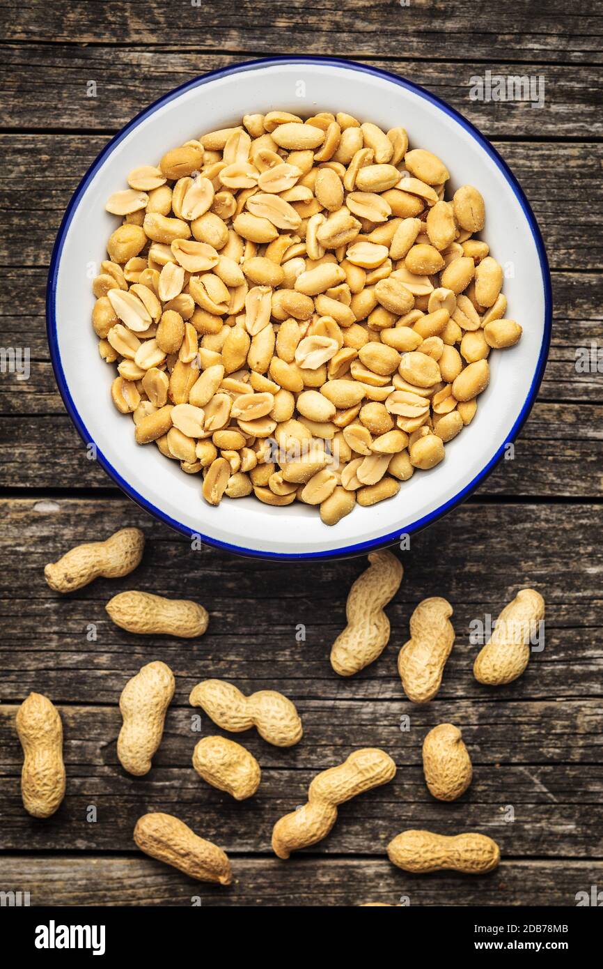 Roasted salted peanuts. Crispy nuts in bowl on wooden table. Top view ...