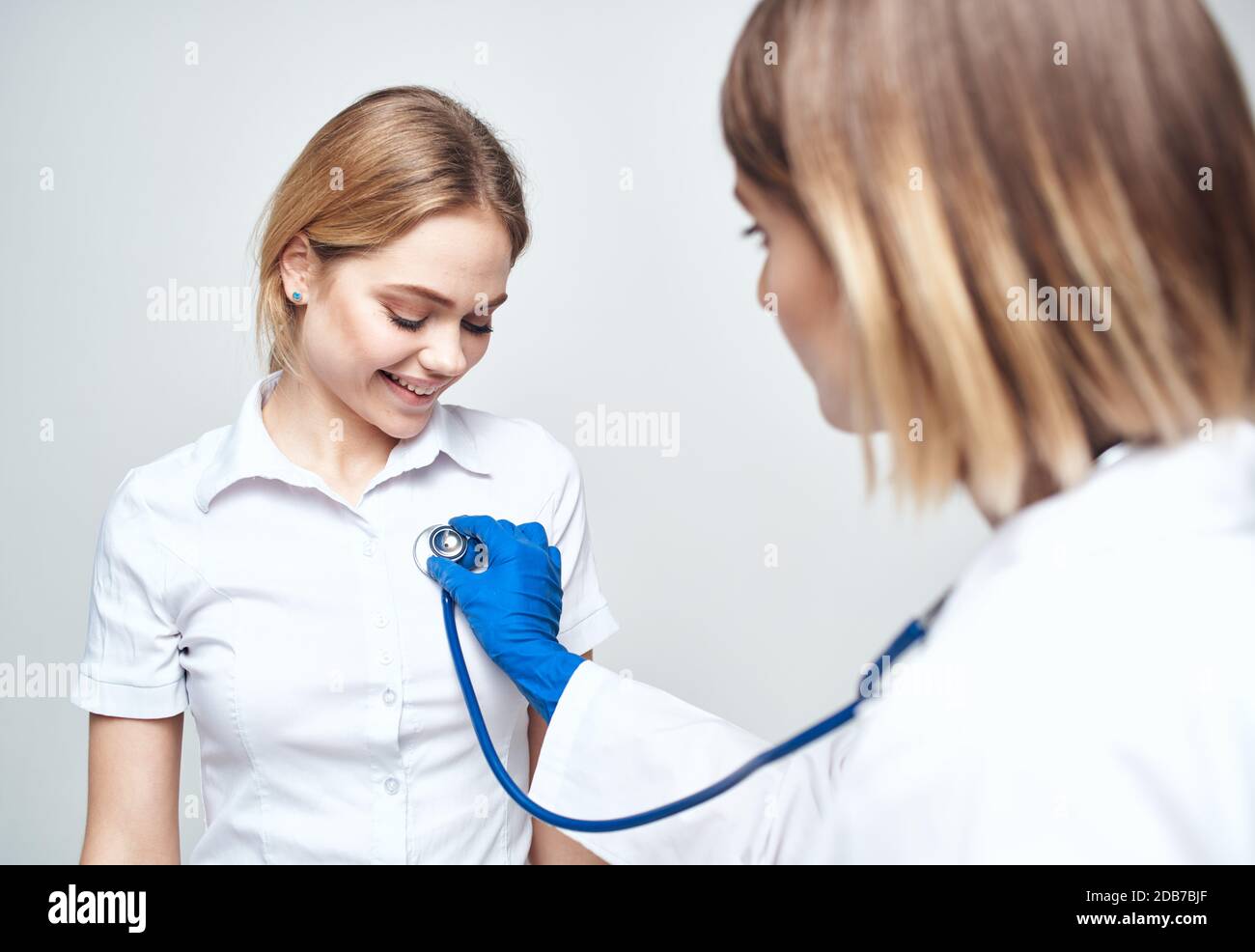 Doctor with a stethoscope and a happy patient on a light background ...