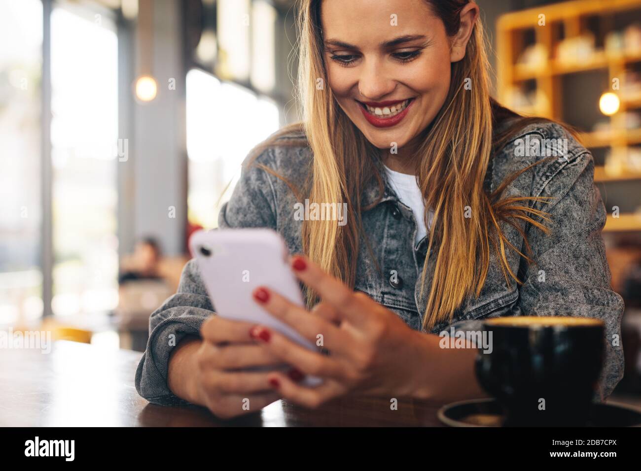 Woman relaxing at the coffee shop using her phone. Smiling female ...