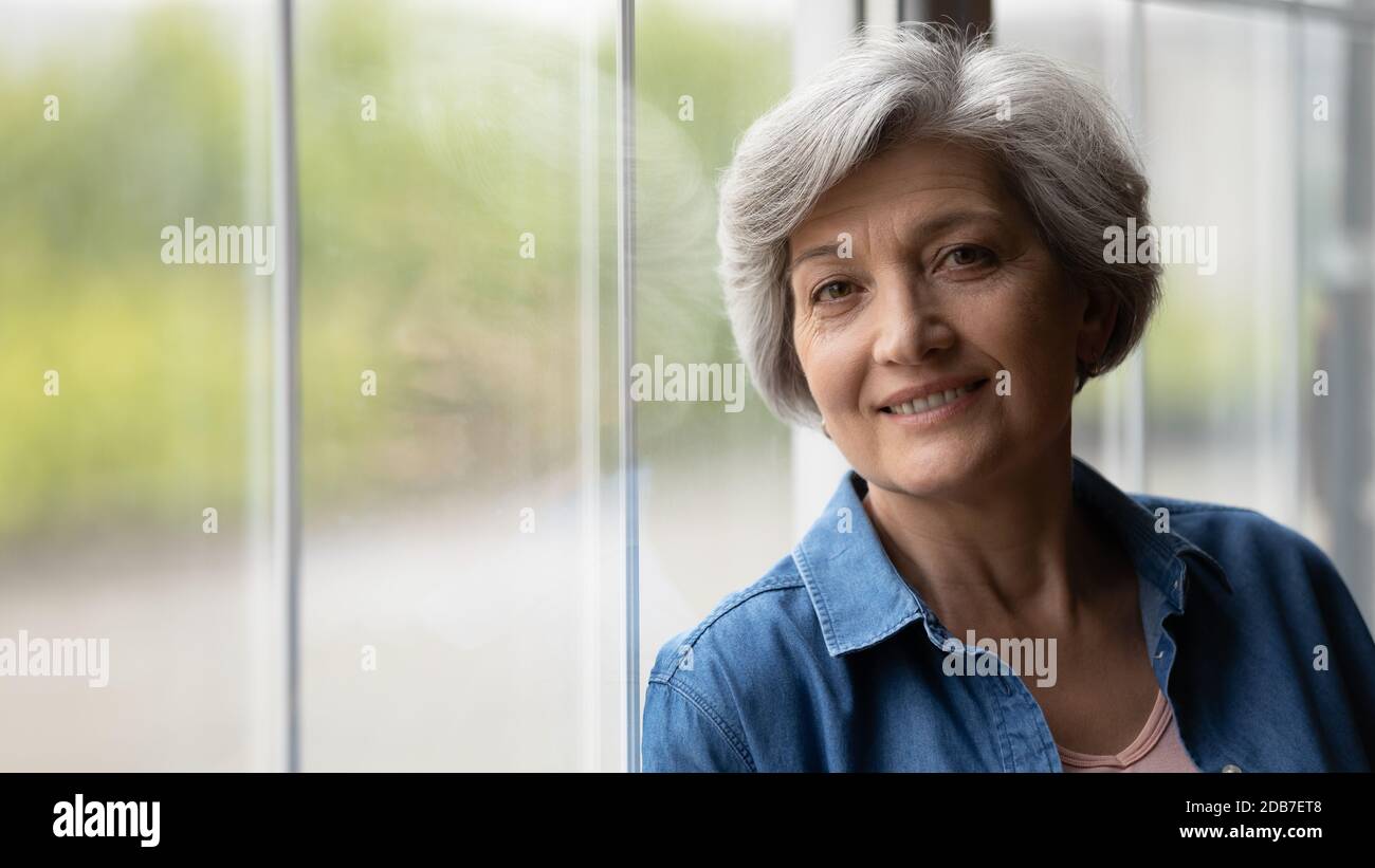 Head shot portrait smiling mature woman standing near window Stock ... Head shot portrait smiling mature woman standing near window Stock ...