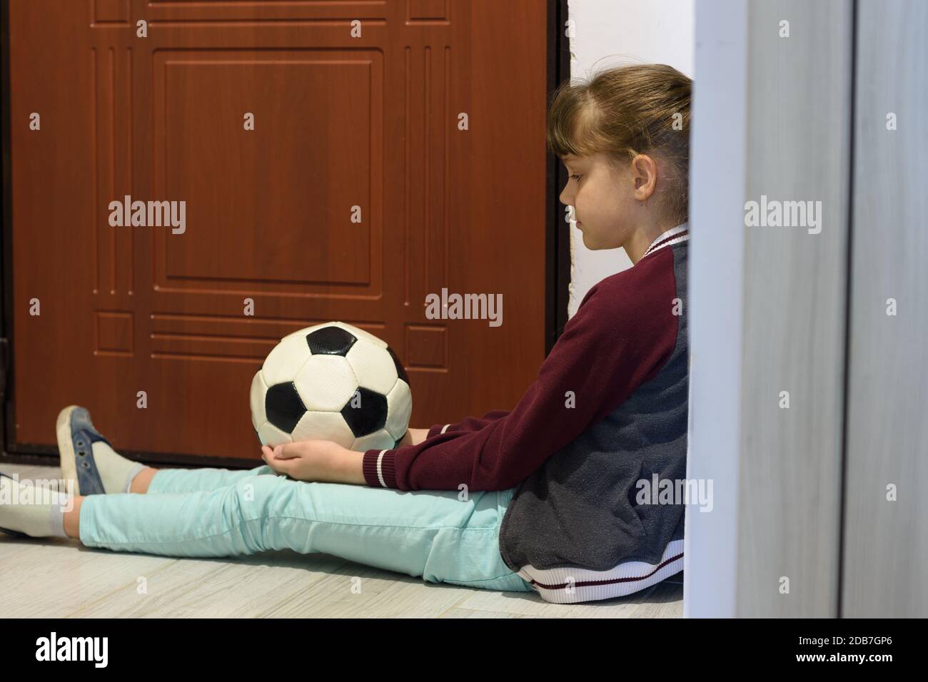 The quarantined girl in self-isolation sits with a ball at the front ...