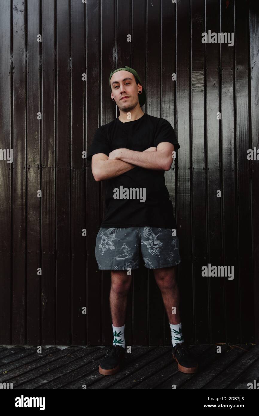 A vertical shot of a young hip male with crossed arms in front of a ...