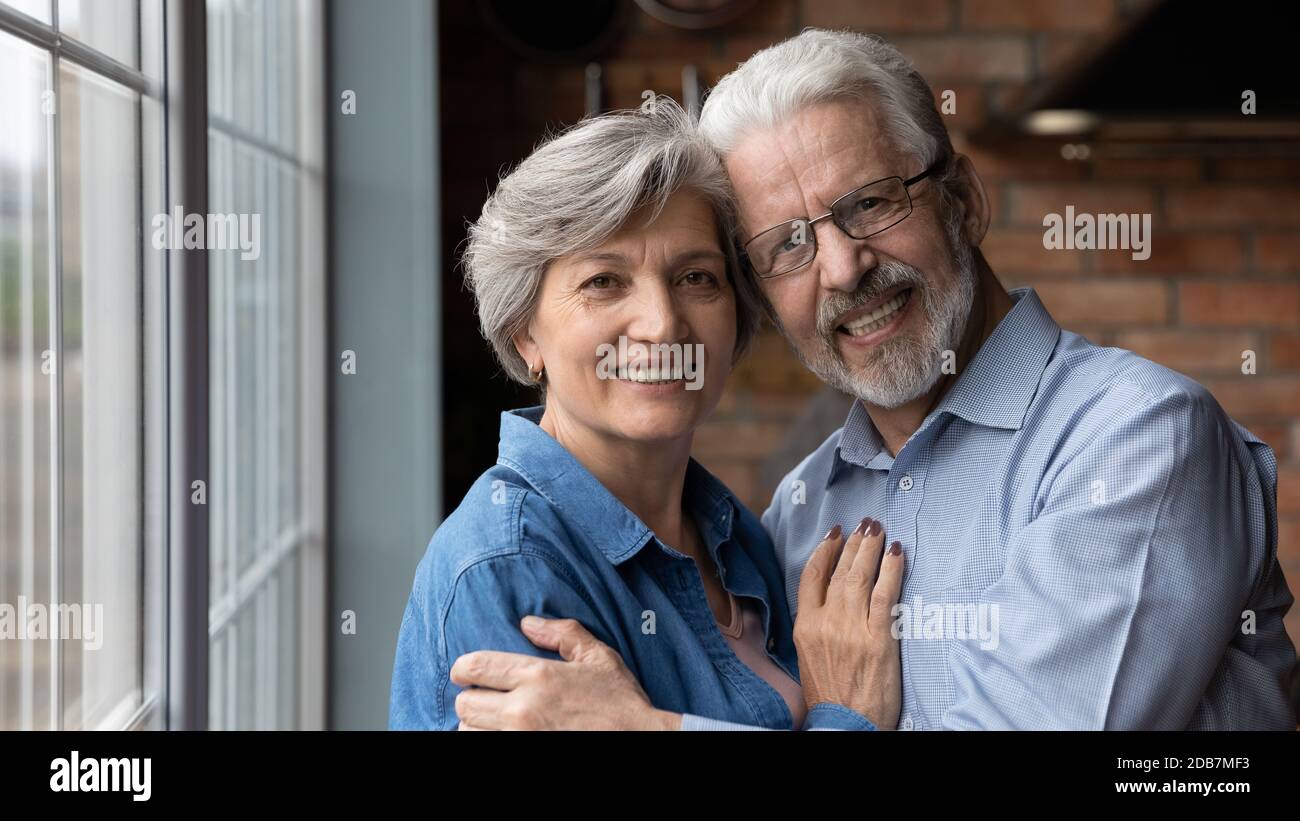 Head shot portrait smiling mature couple hugging, looking at camera ...