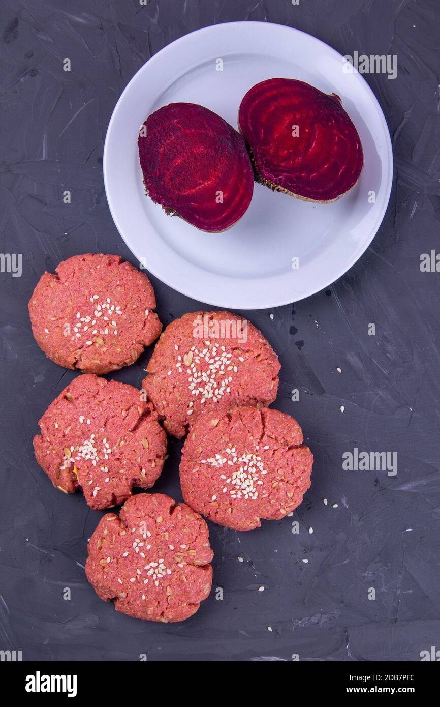 Beetroot oatmeal cookie stands black background, next to a white plate ...