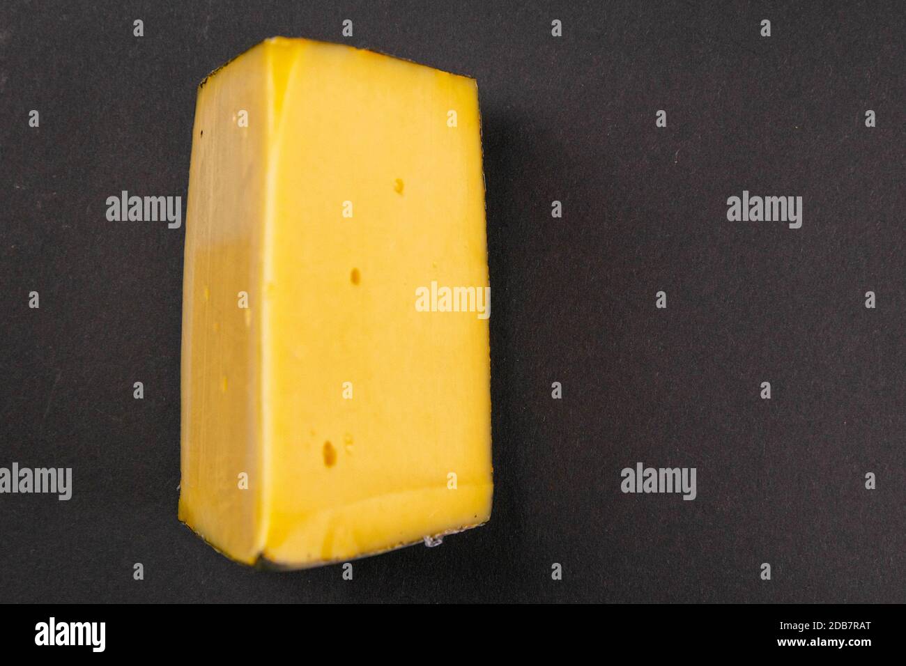 a large piece of Swiss cheese on a black background. side view. Milk ...