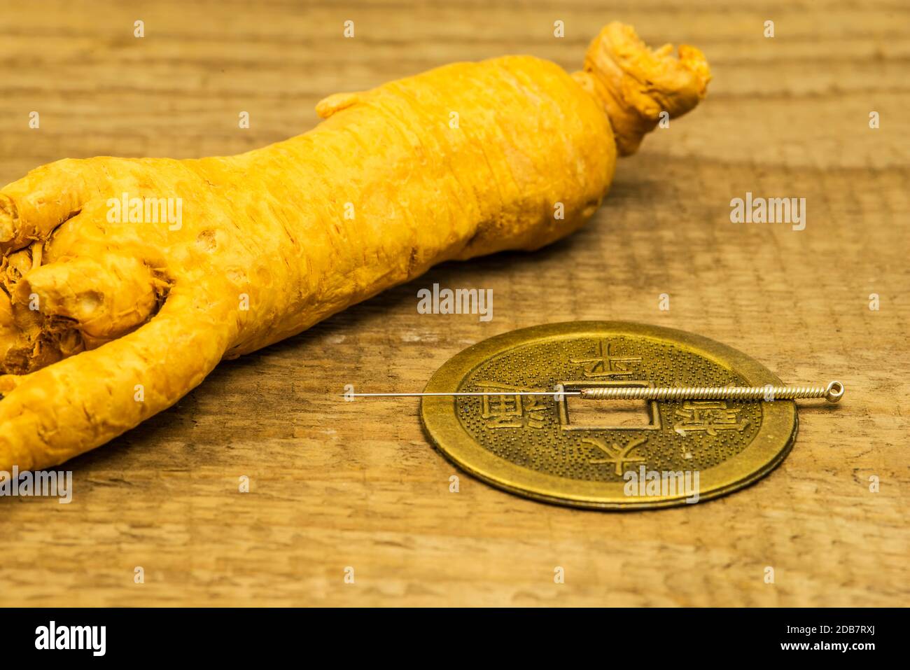 Acupuncture needle on Chinese coin with ginseng root Stock Photo - Alamy