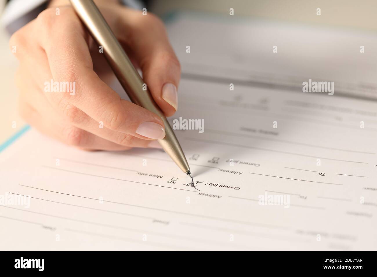 Close up of woman hands filling out form checking yes box on a desk ...