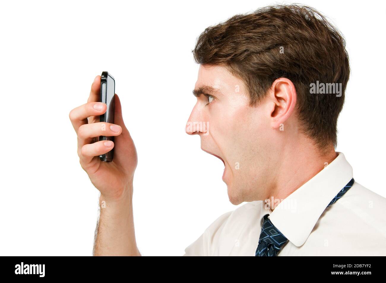 Head-and-shoulder view of a young man in profile angrily yelling at a ...