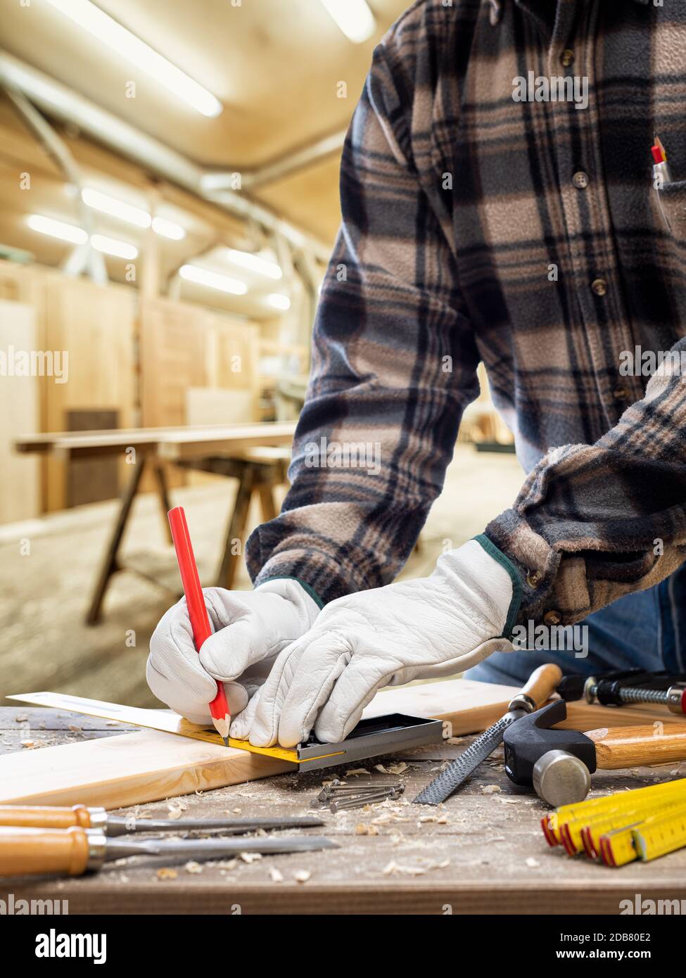 Close-up. Carpenter with his hands protected by gloves with pencil and ...