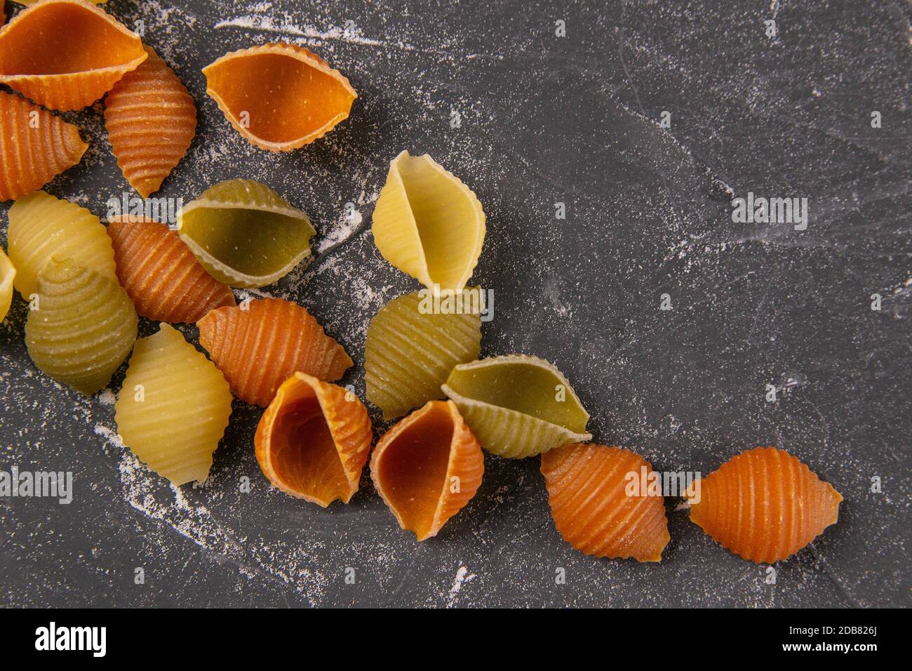 Pasta Conchiglie Rigate, mix of colorful uncooked shells scattered on ...