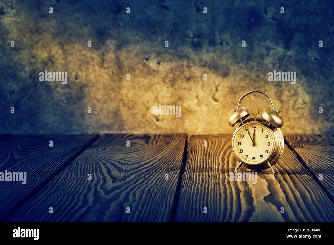 Old alarm clock under beam of light on wooden table Stock Photo - Alamy