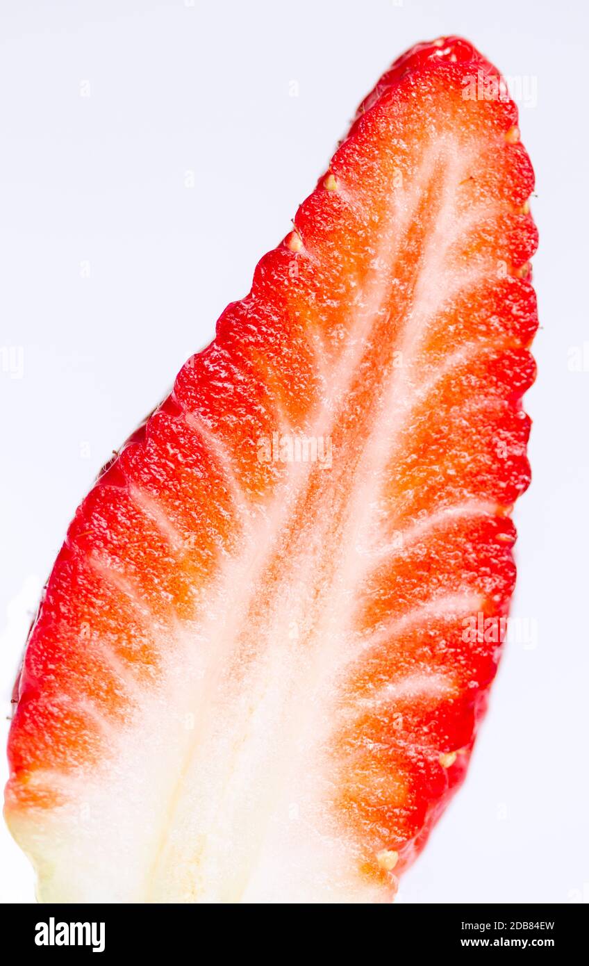 Close-up of a fresh, bright red strawberry cut in half in portrait ...