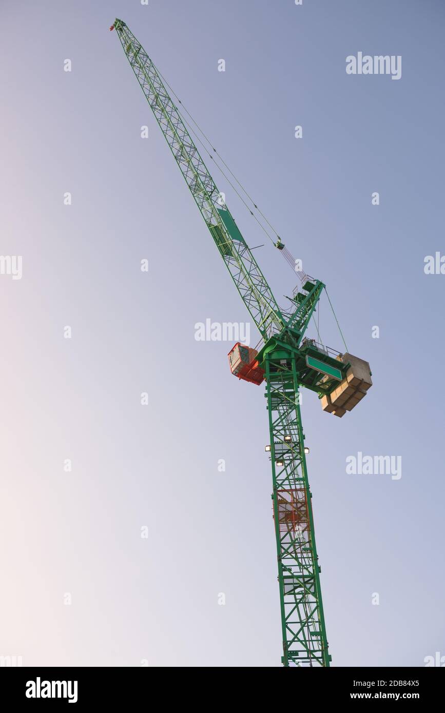 Top portion a tall tower crane at sunrise with a bright sky background ...