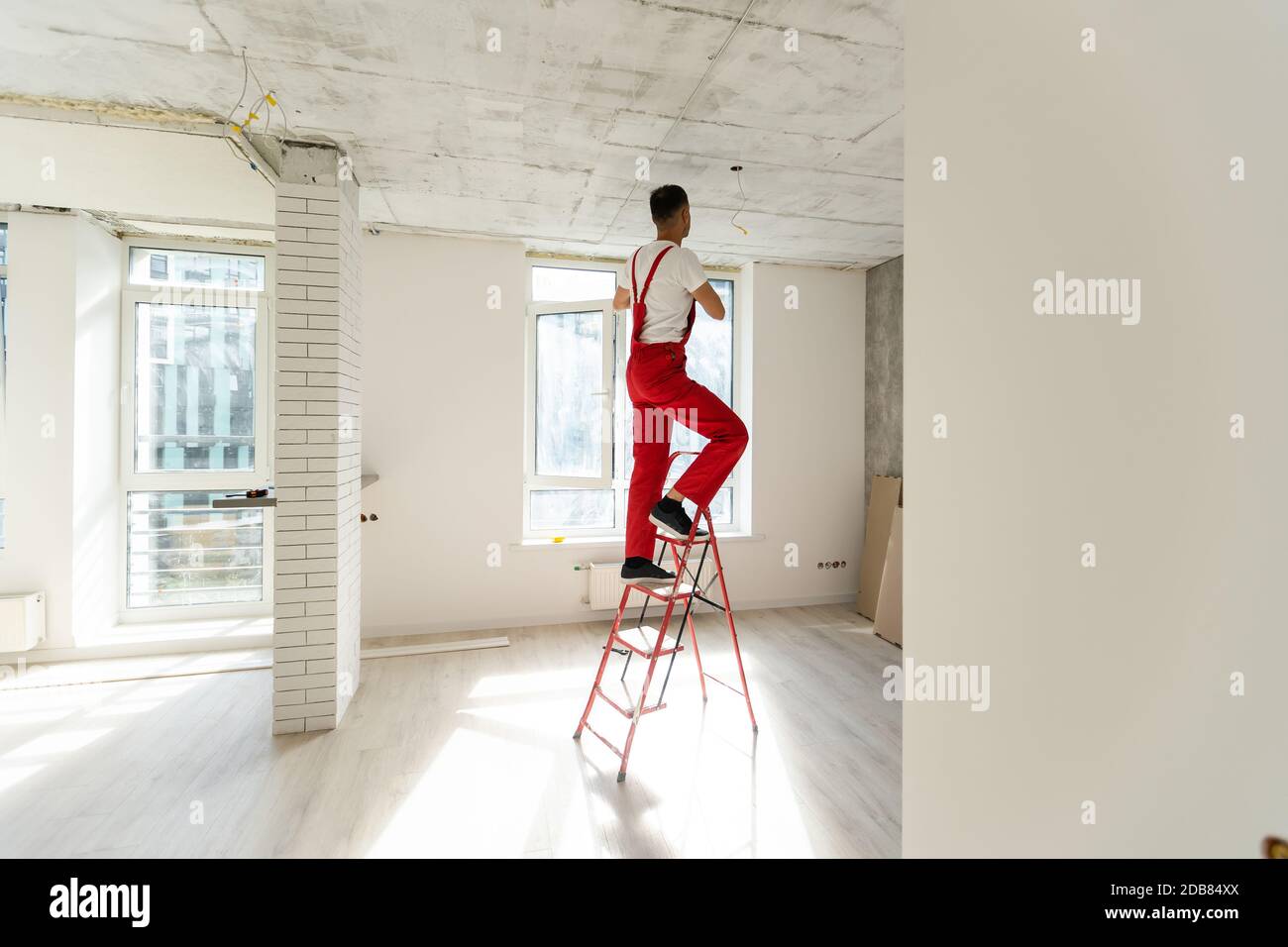 Electrician mounts halogen lamp in ceiling light in room Stock Photo ...