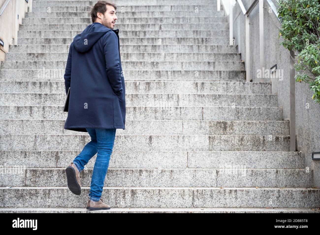 Horizontal portrait of young attractive man standing on steps looking ...