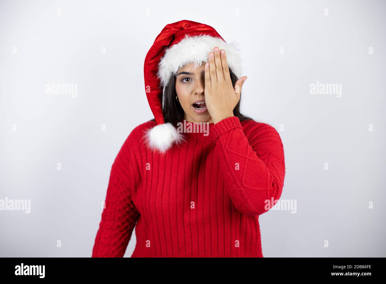 Young beautiful woman wearing a Santa hat over white background ...